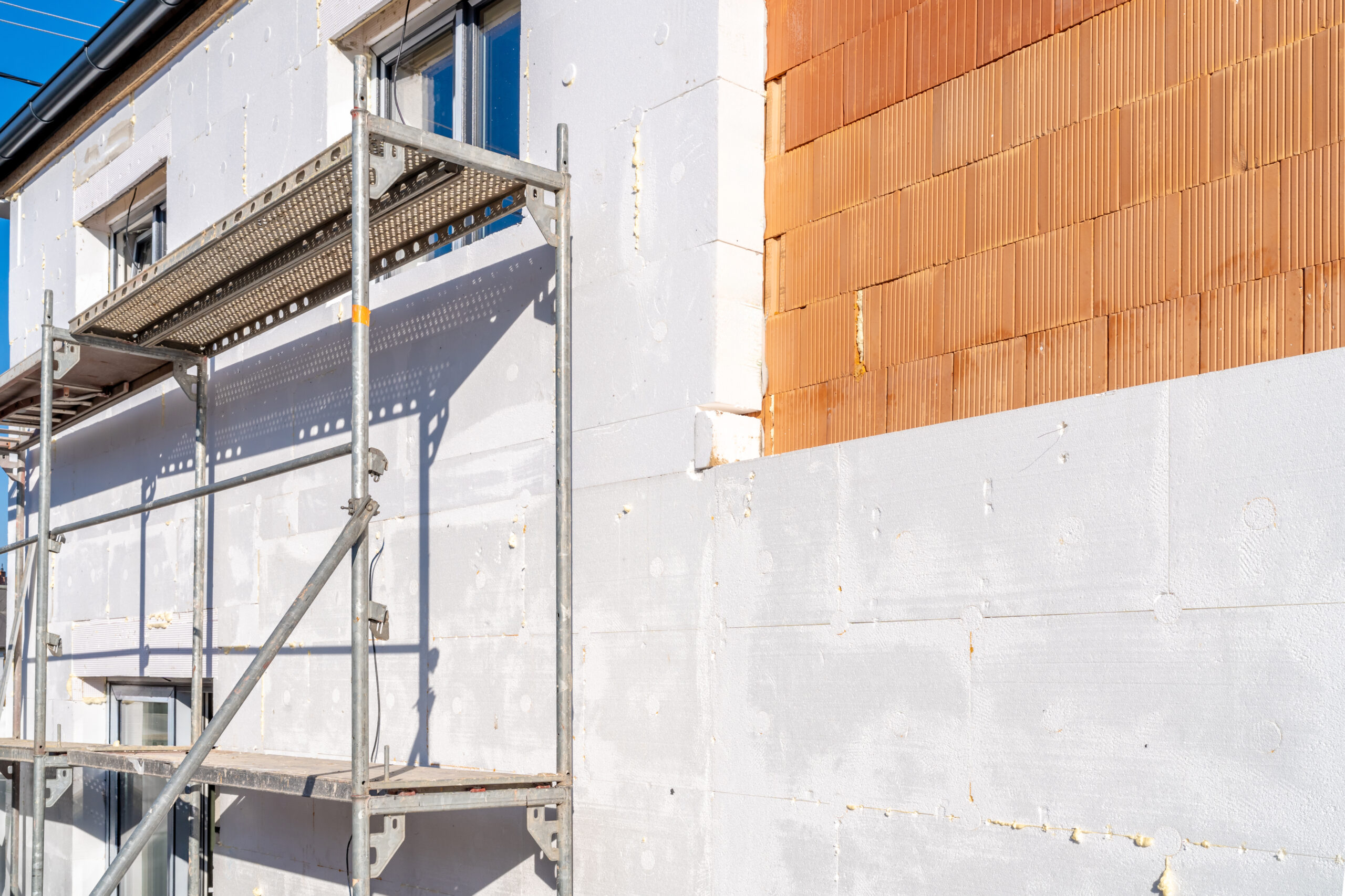 Workers installing external thermal insulation with scaffolding on ...
